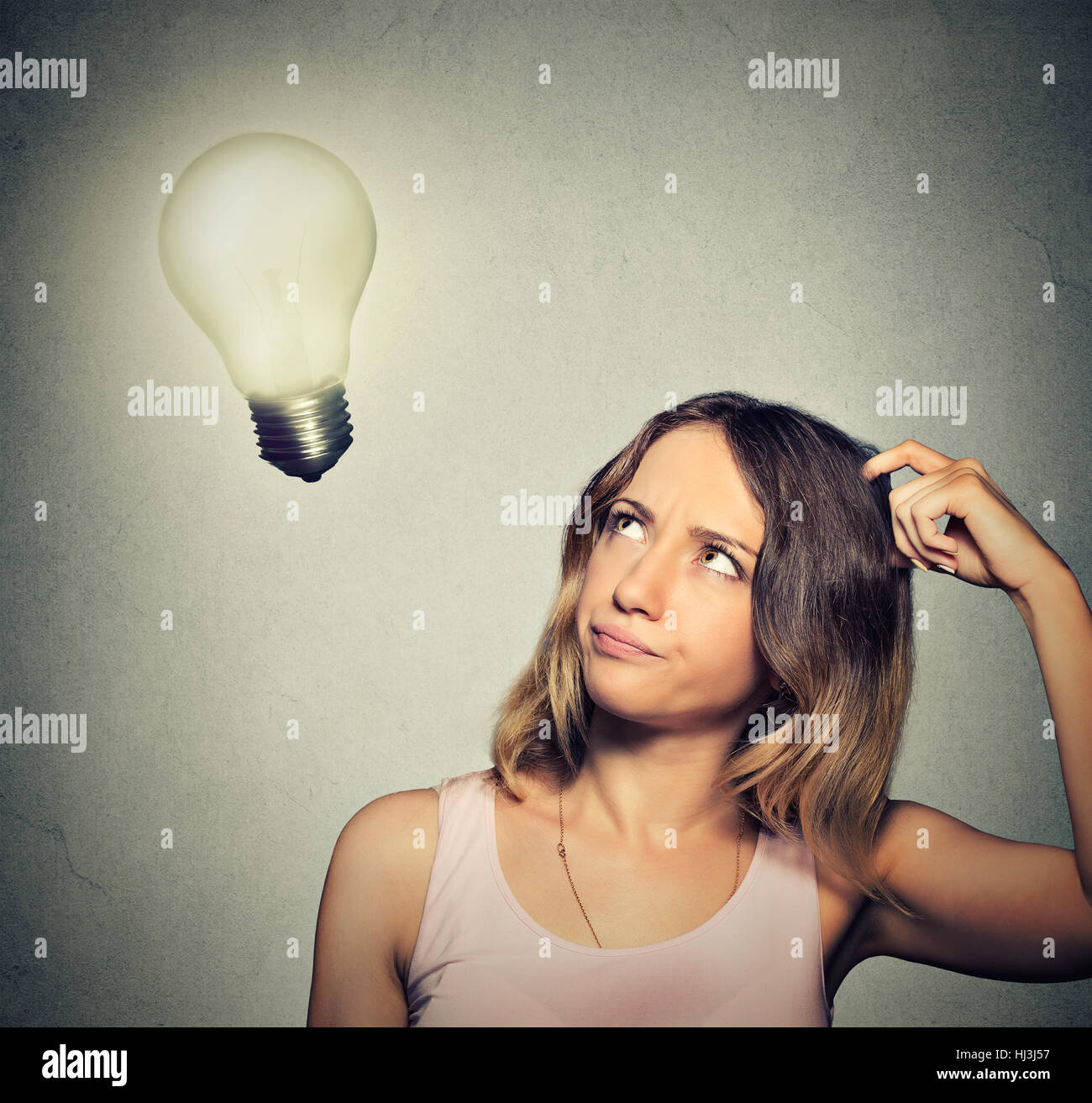 Closeup portrait beautiful girl thinks looking up at bright light bulb ...