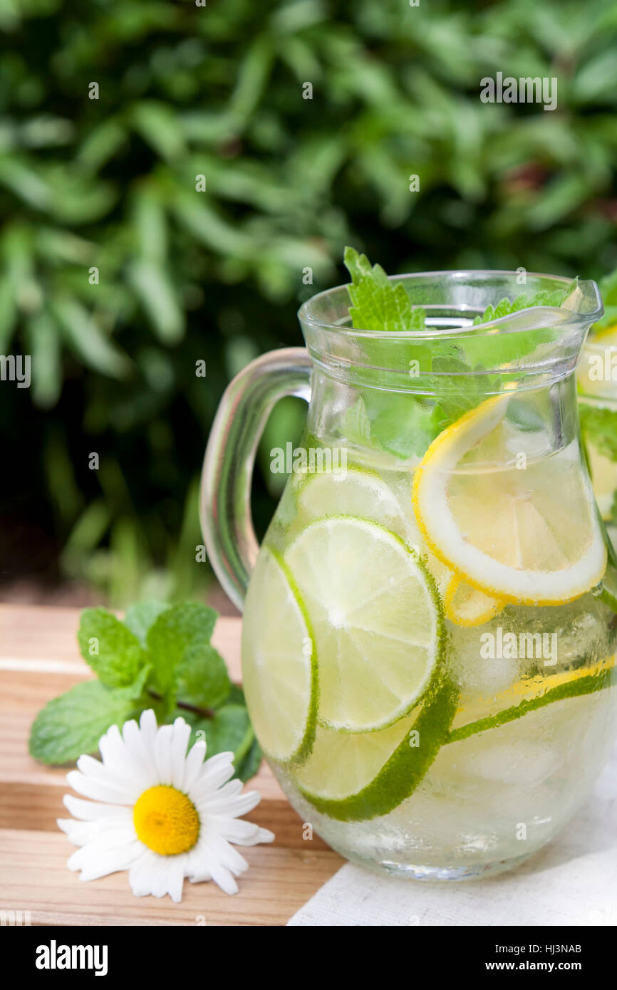 Cold fresh lemonade with lemon, lime and fresh mint on wooden table ...