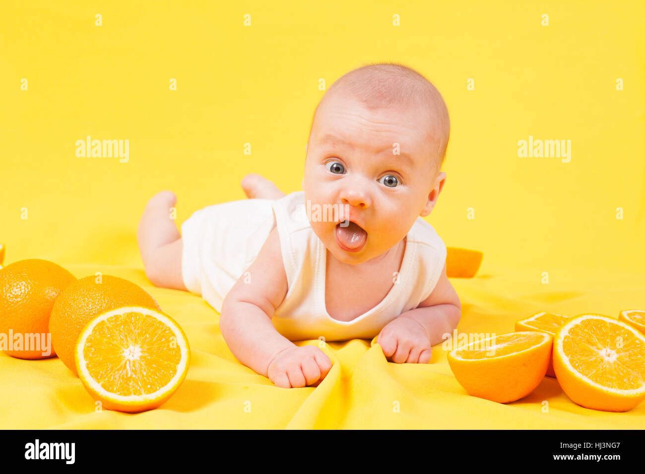 baby boy lies on a yellow with oranges Stock Photo - Alamy