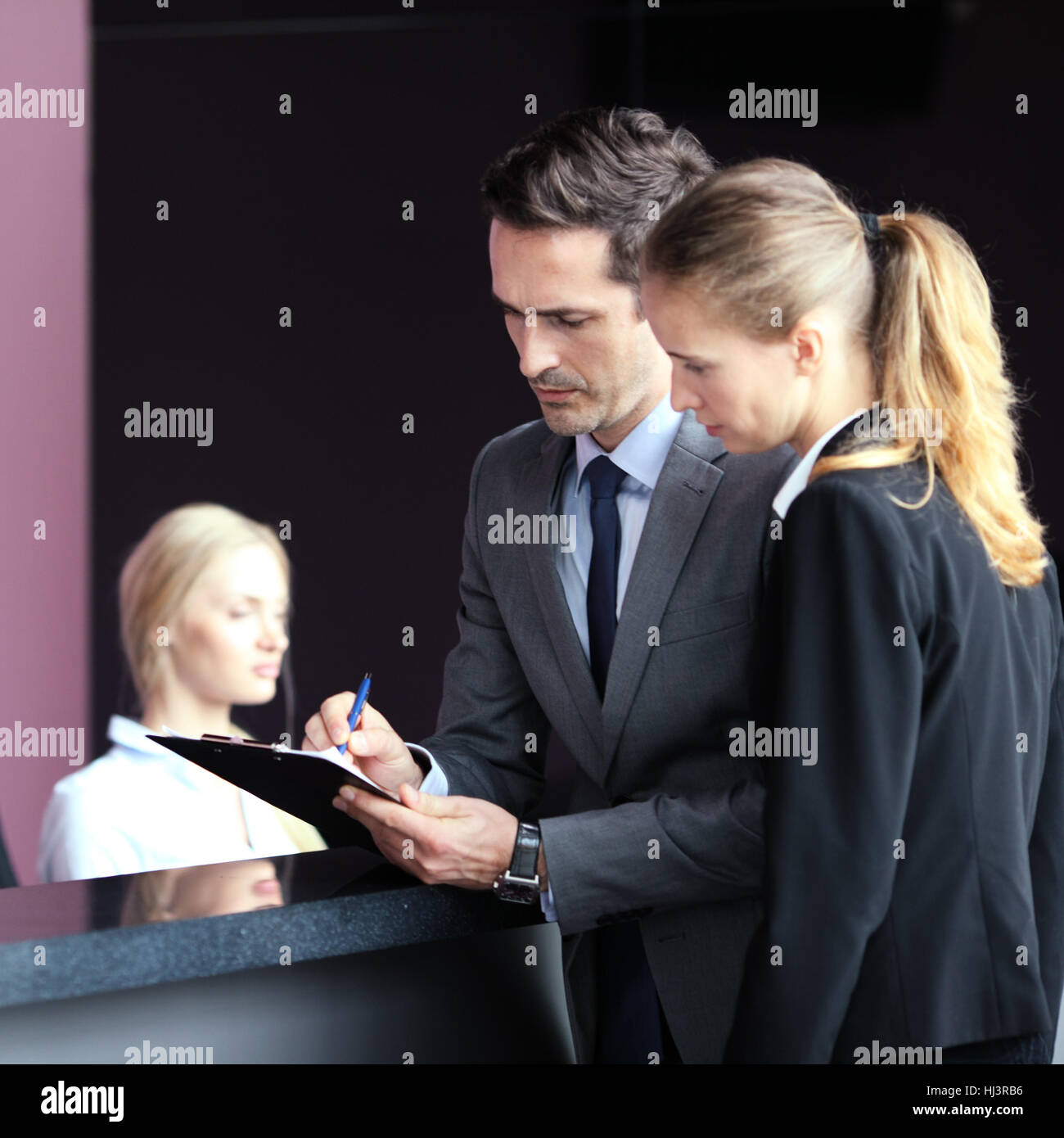 Business people filling forms at reception front desk Stock Photo - Alamy