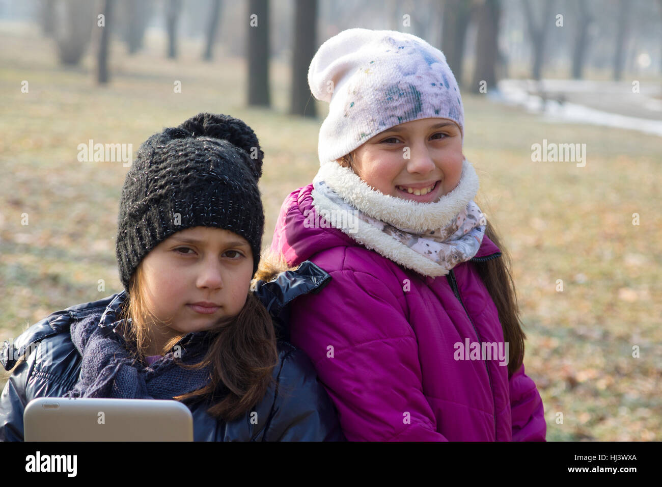 Two little girls with caps and scarves play Stock Photo - Alamy