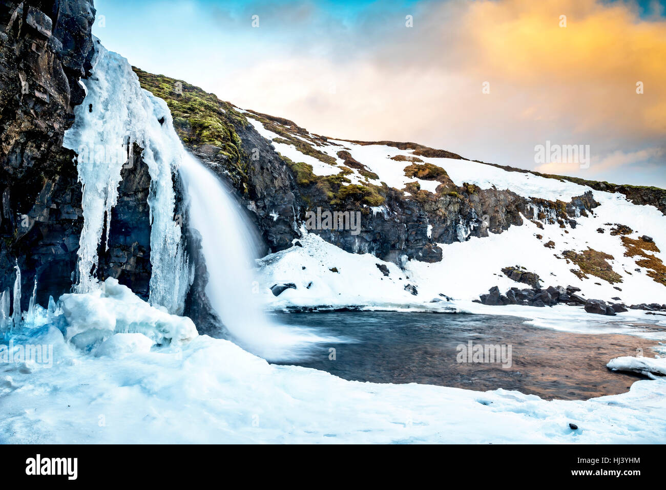 A cold snowy waterfall in the highlands of Iceland framed by pastel ...