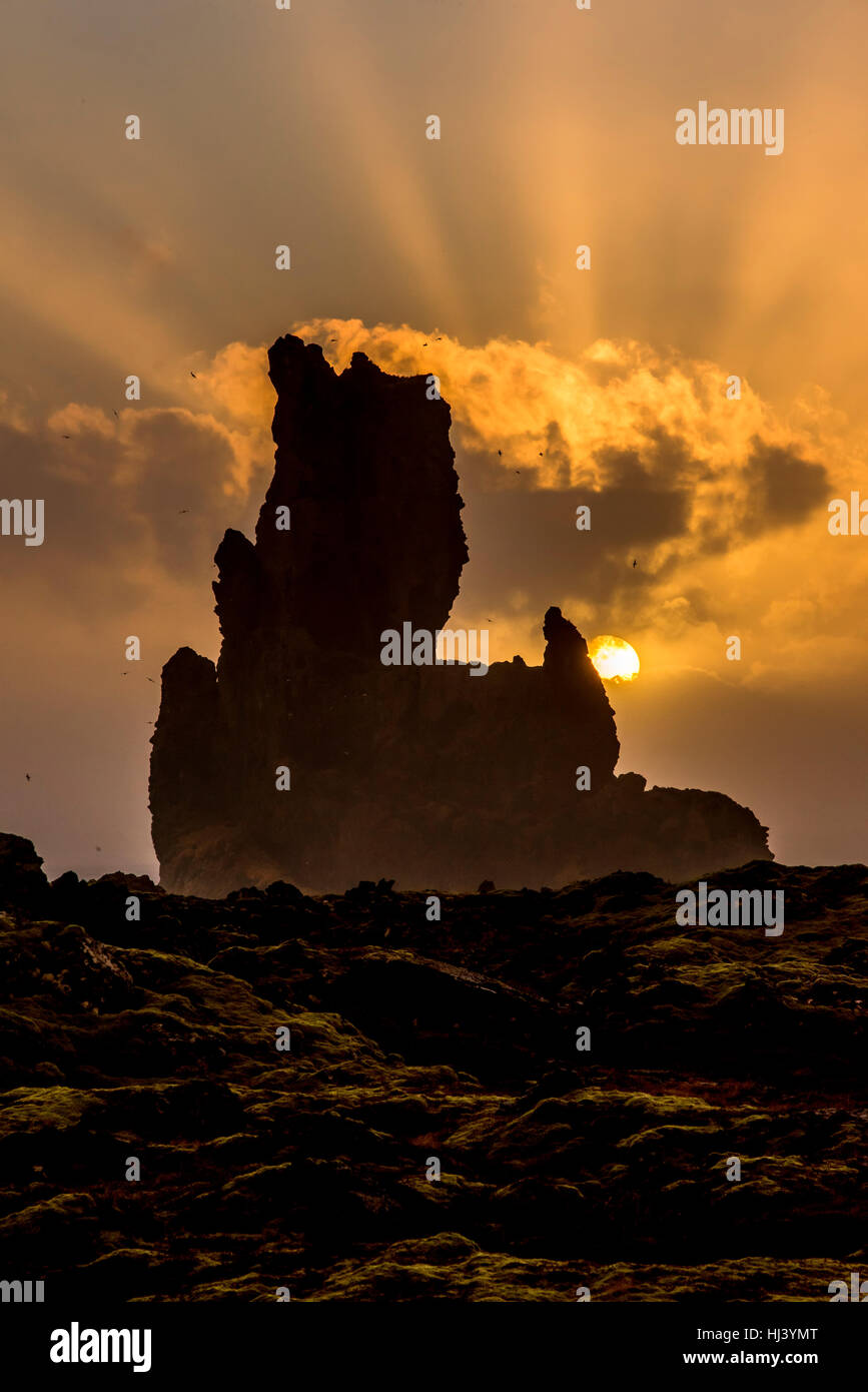 Sunset over an oceanfront landscape shows very moody, dark terrain ...