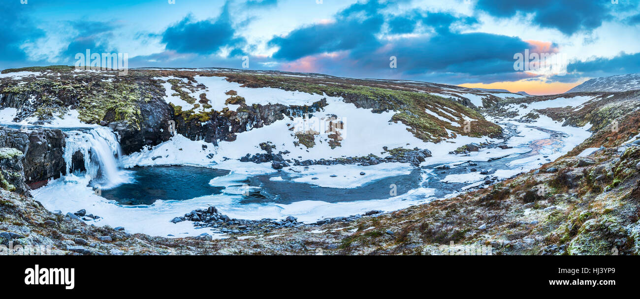 A cold snowy waterfall in the highlands of Iceland framed by pastel ...