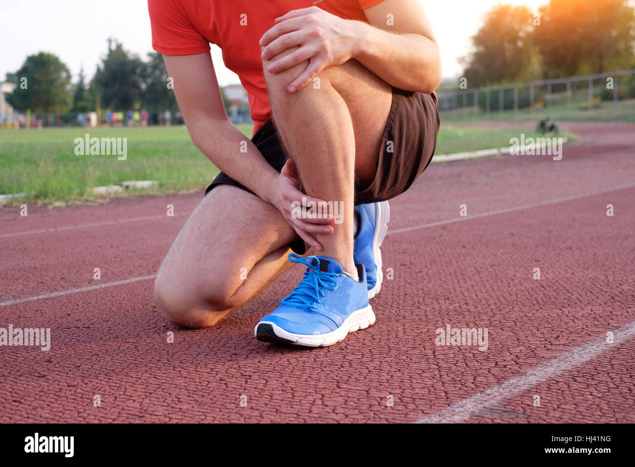 Runner with injured ankle on the track Stock Photo - Alamy