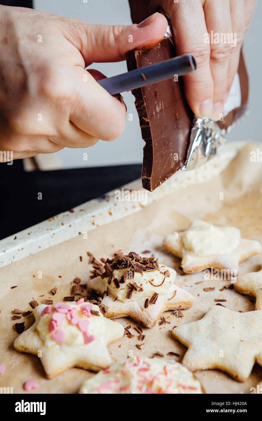 Hands of person adds chocolate as a cookies topping. Vertical studio ...
