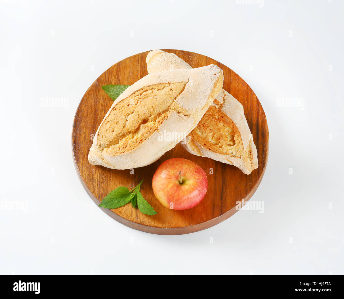 diamond shaped ciabatta bread and fresh apple on round wooden cutting ...