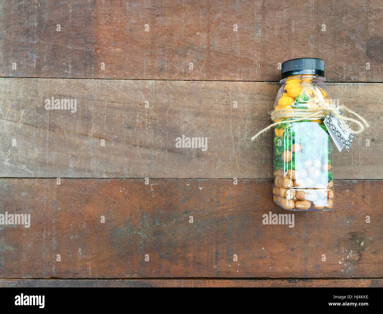 Variety of nuts and peanuts in the plastic bottle on the wooden table ...