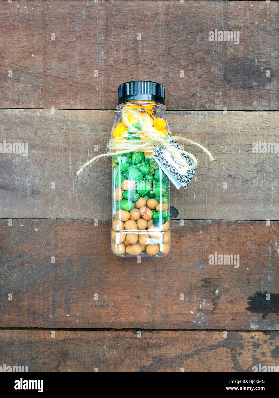 Variety of nuts and peanuts in the plastic bottle on the wooden table ...