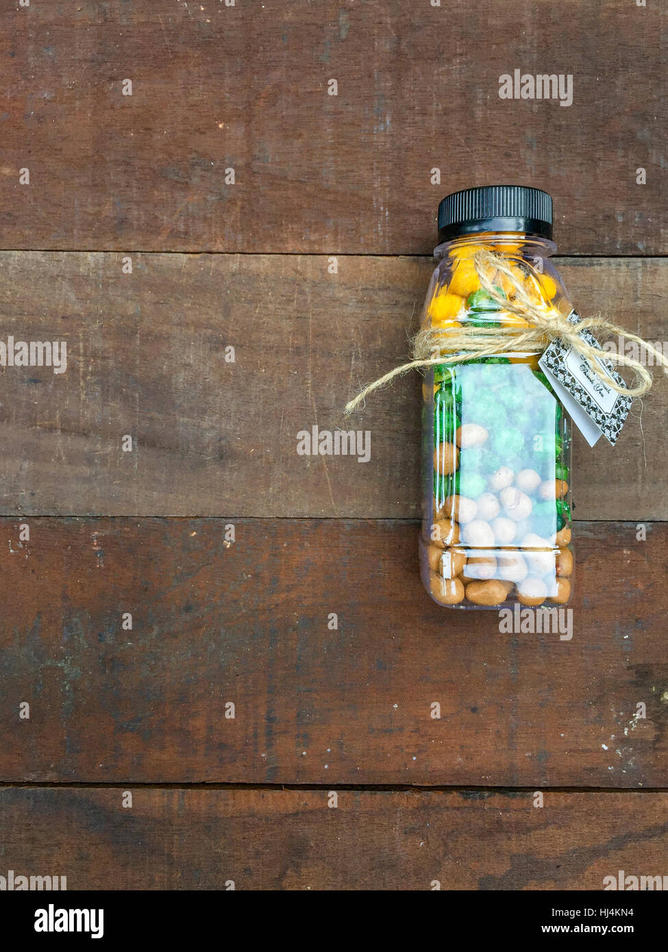 Variety of nuts and peanuts in the plastic bottle on the wooden table ...