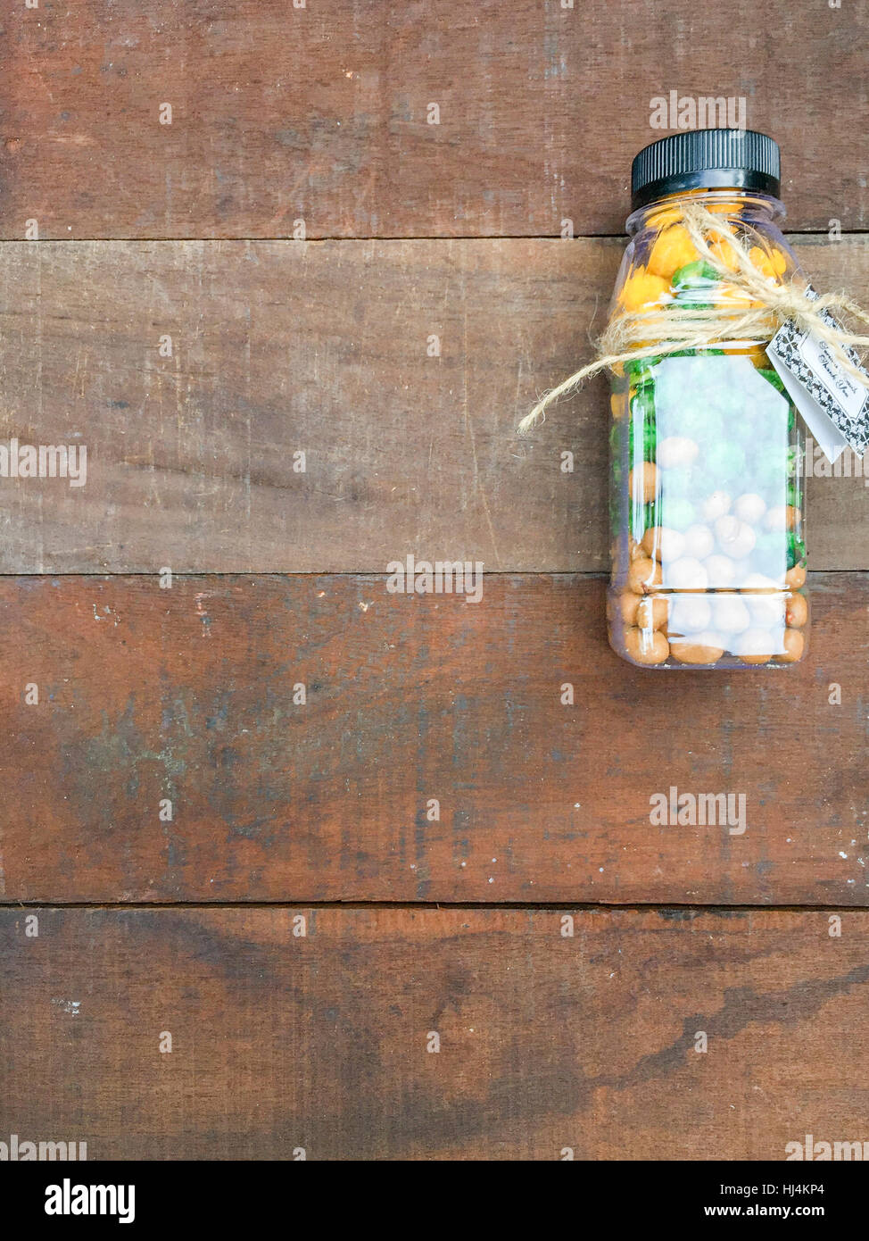 Variety of nuts and peanuts in the plastic bottle on the wooden table ...