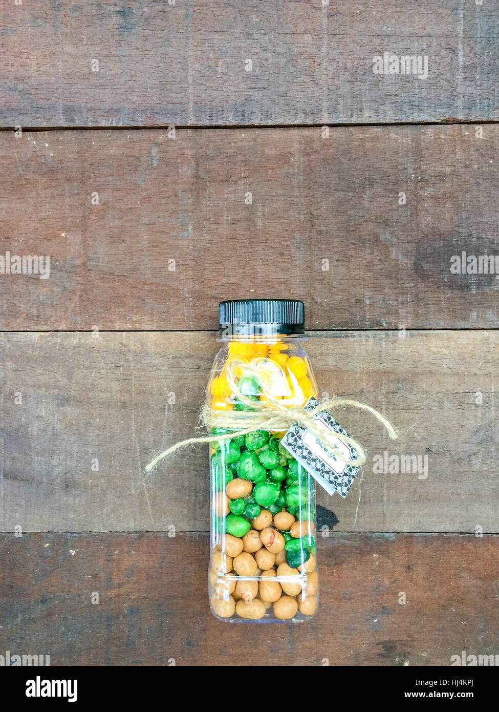 Variety of nuts and peanuts in the plastic bottle on the wooden table ...