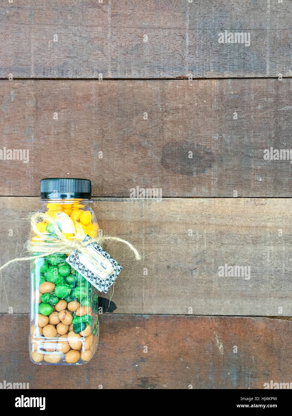 Variety of nuts and peanuts in the plastic bottle on the wooden table ...
