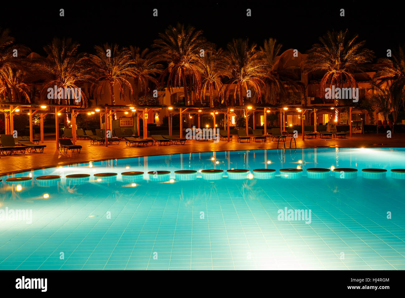 illuminated pool at night with tropical palms in background, Egypt ...