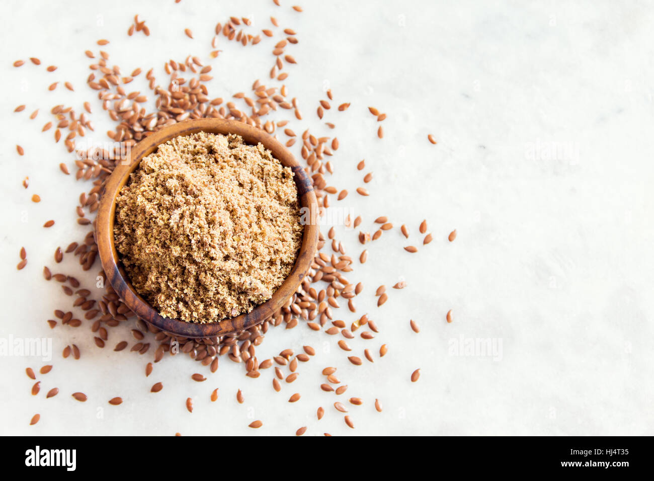 Bowl of crushed flax seeds (ground linseed) on white stone table ...