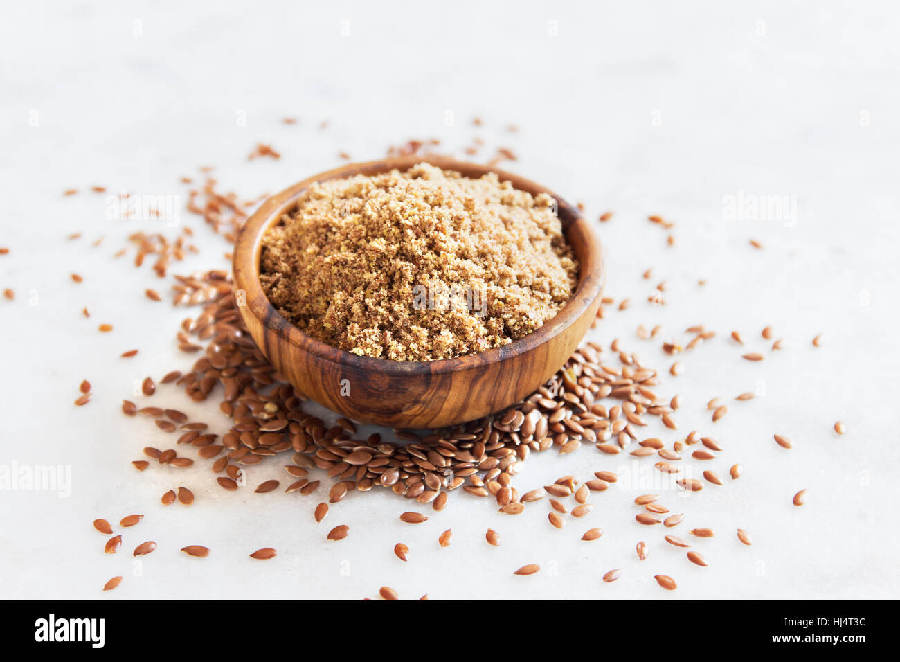 Bowl of crushed flax seeds (ground linseed) on white stone table ...