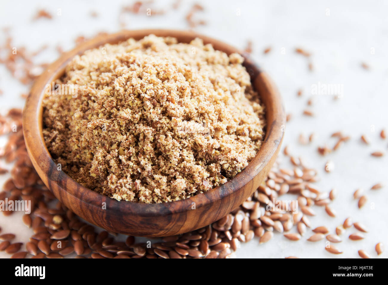 Bowl of crushed flax seeds (ground linseed) on white stone table ...