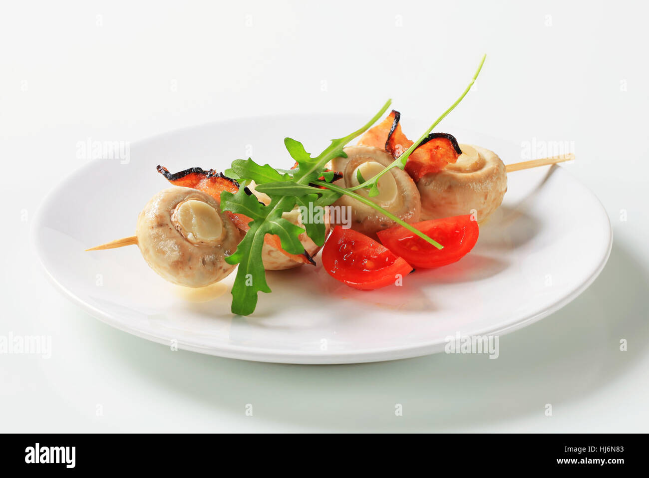 Skewer of button mushrooms with crispy bacon and rocket Stock Photo - Alamy