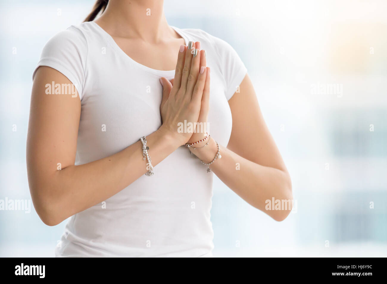 Woman in white t-shirt making namaste gesture, closeup Stock Photo - Alamy