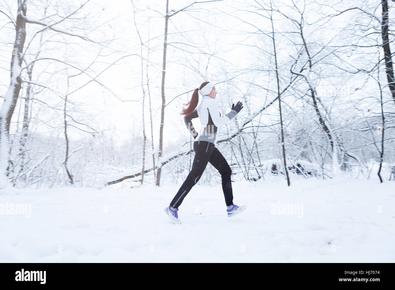 Brunette running in winter park Stock Photo - Alamy