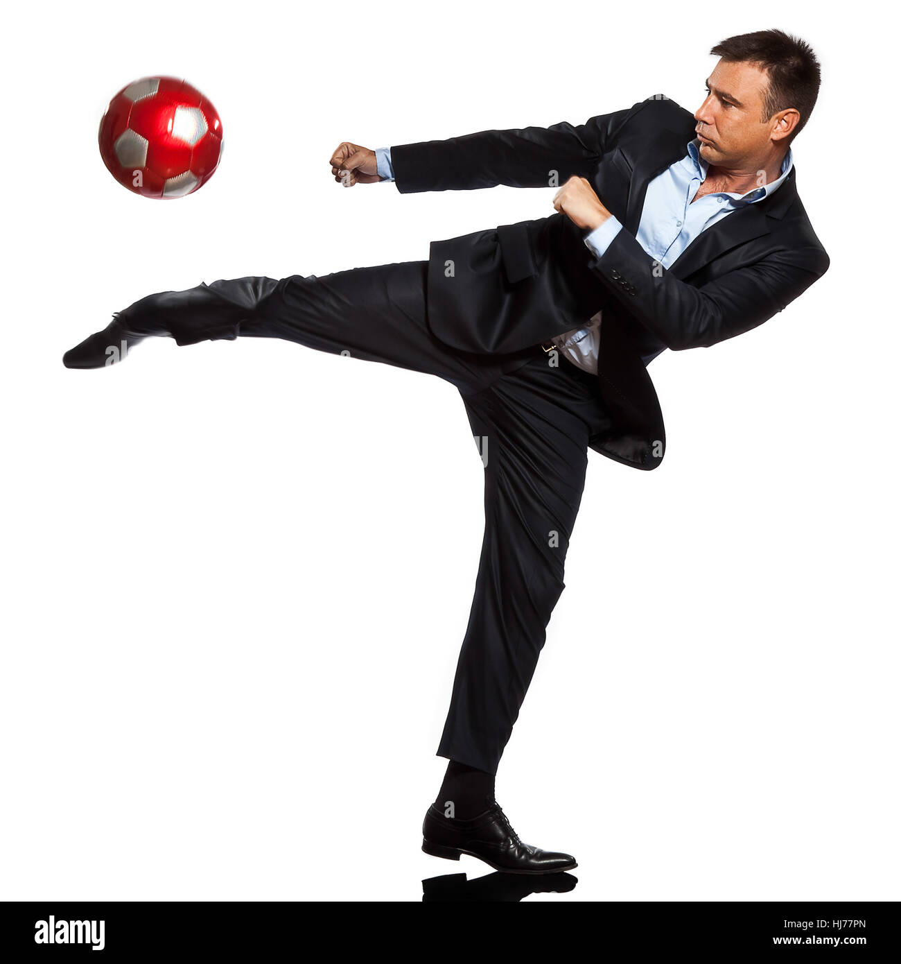 one caucasian business man playing kicking soccer ball in studio ...