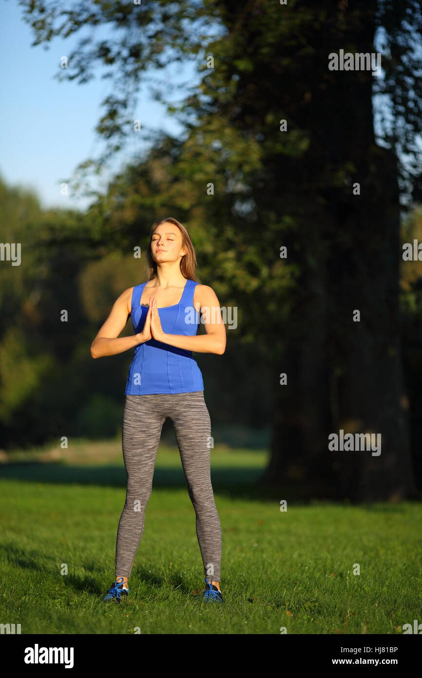 Young woman standing in park with praying hands Stock Photo - Alamy