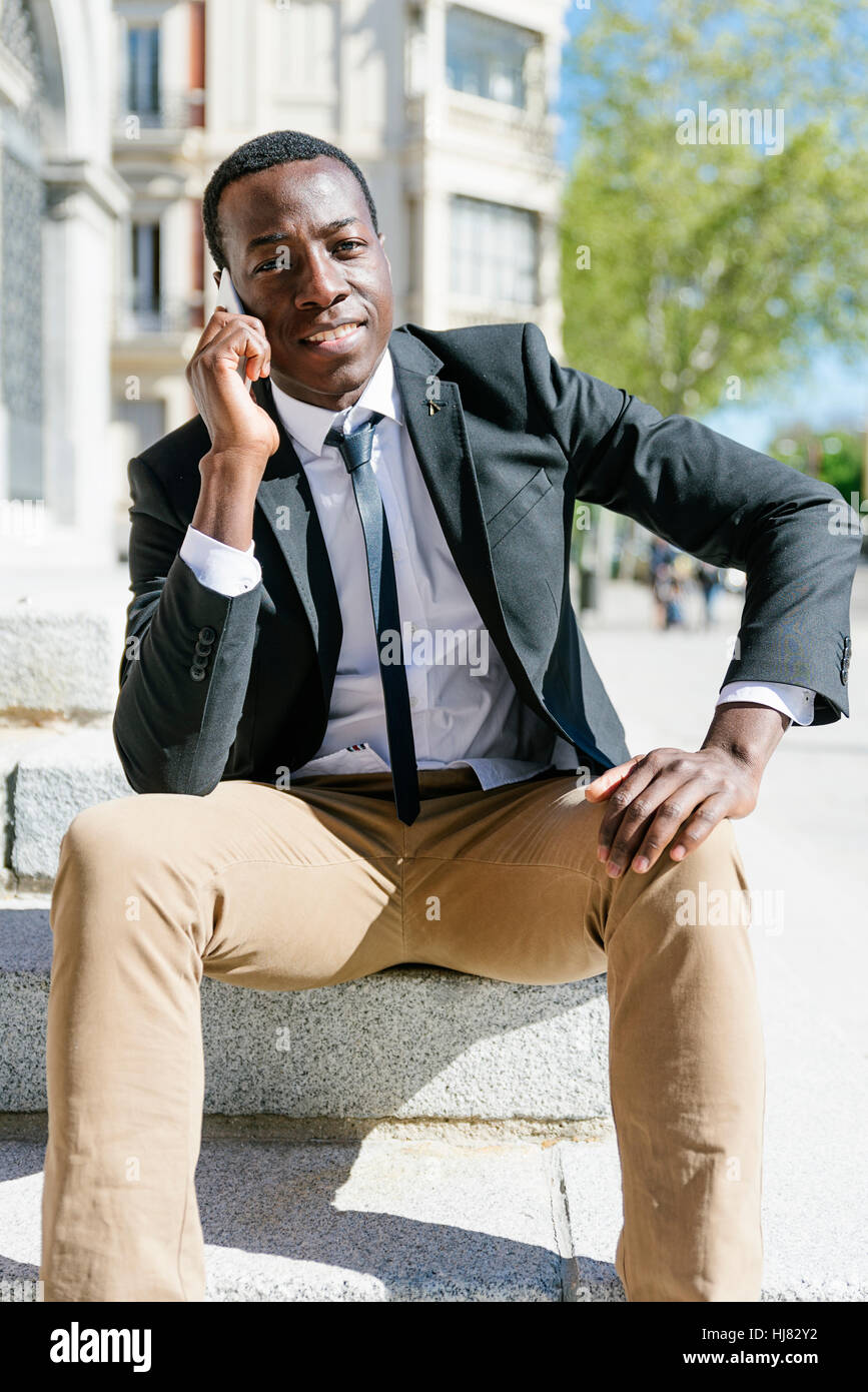 Portrait of Handsome african man smiling when he is using his mobile in ...