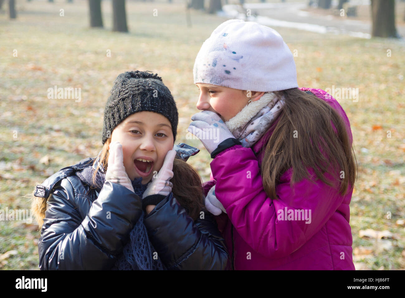 Two little girls with caps and scarves play Stock Photo - Alamy