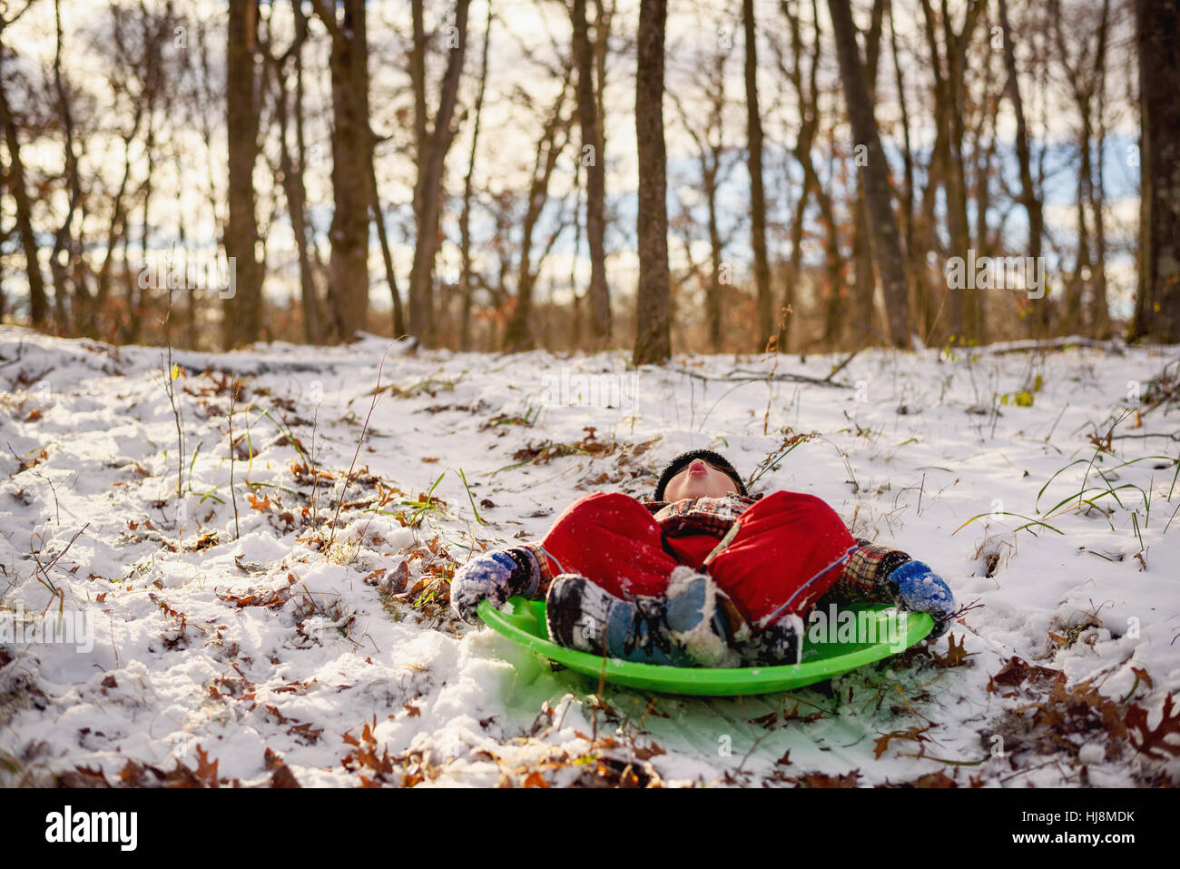 Boy lying in a sledge making a funny face Stock Photo - Alamy