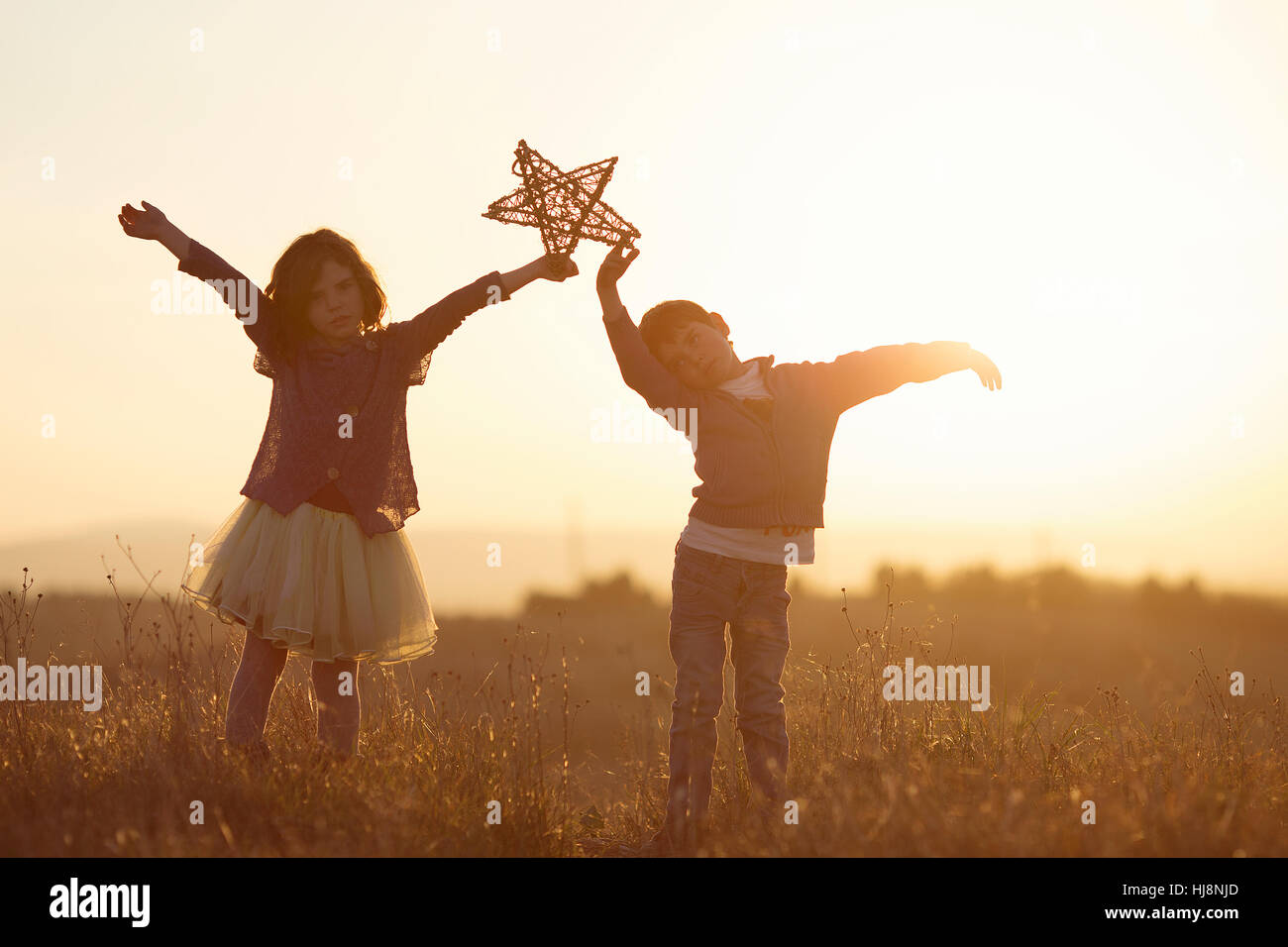 Two children holding a star in the air Stock Photo - Alamy
