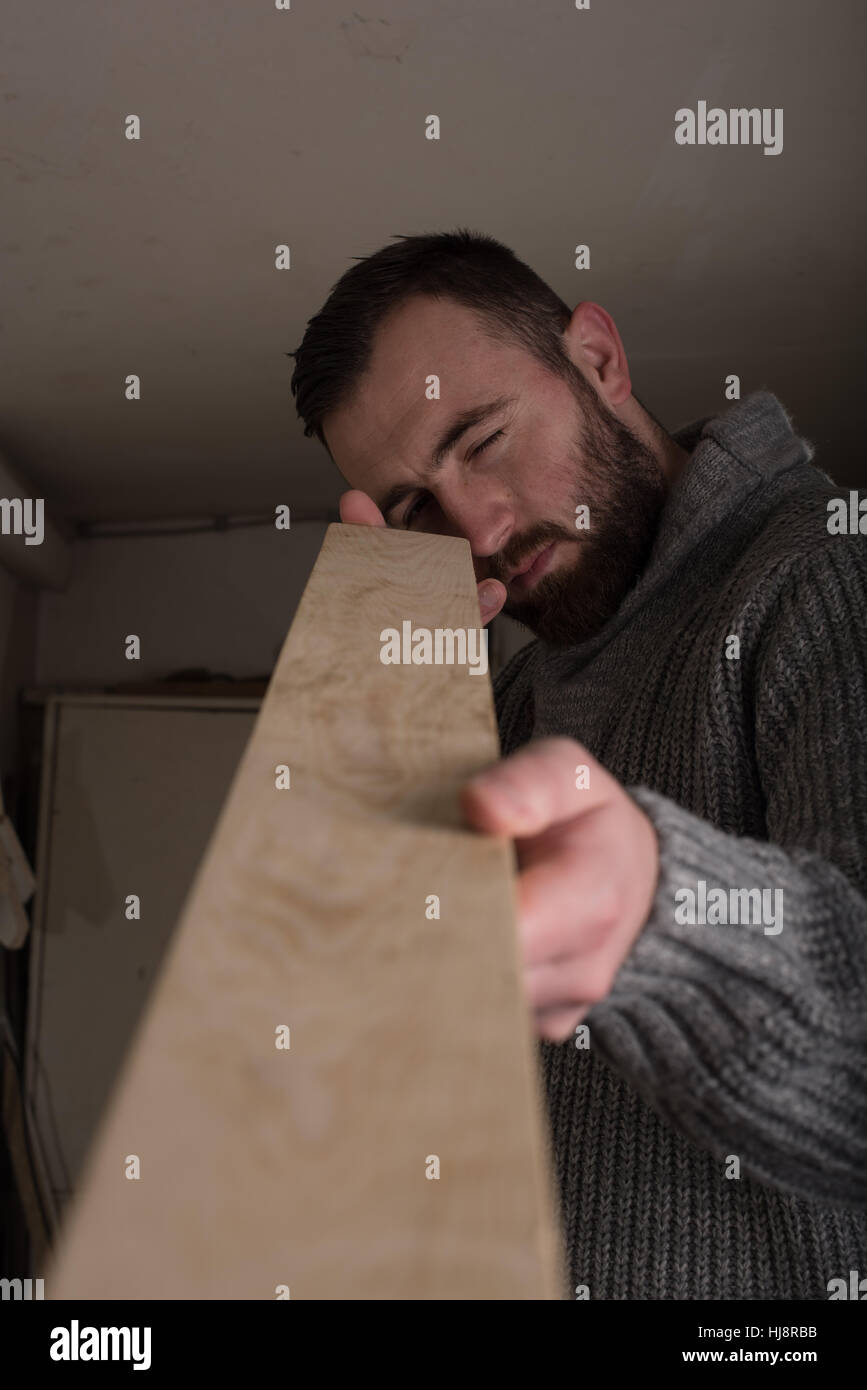 Carpenter looking at wooden plank Stock Photo - Alamy
