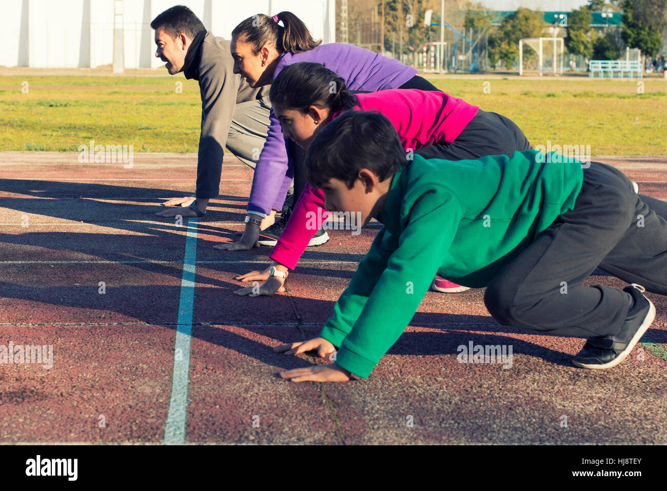 Family waiting at starting line on running track Stock Photo - Alamy