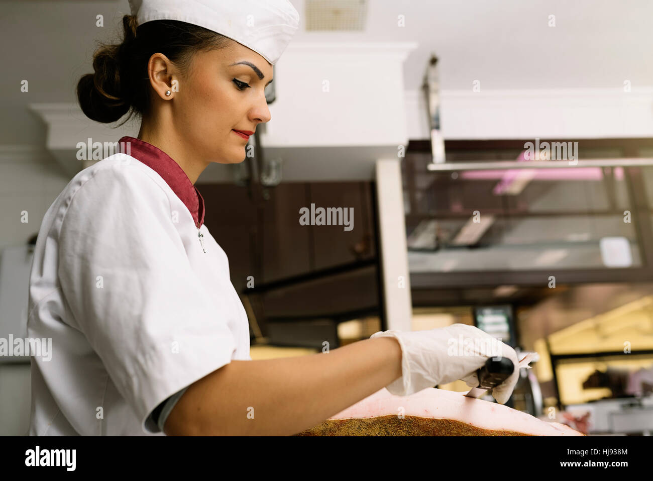 Pretty butchery woman cutting ham with knife Stock Photo - Alamy