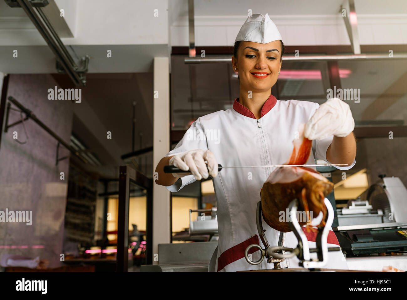 Pretty butchery woman cutting ham with knife Stock Photo - Alamy