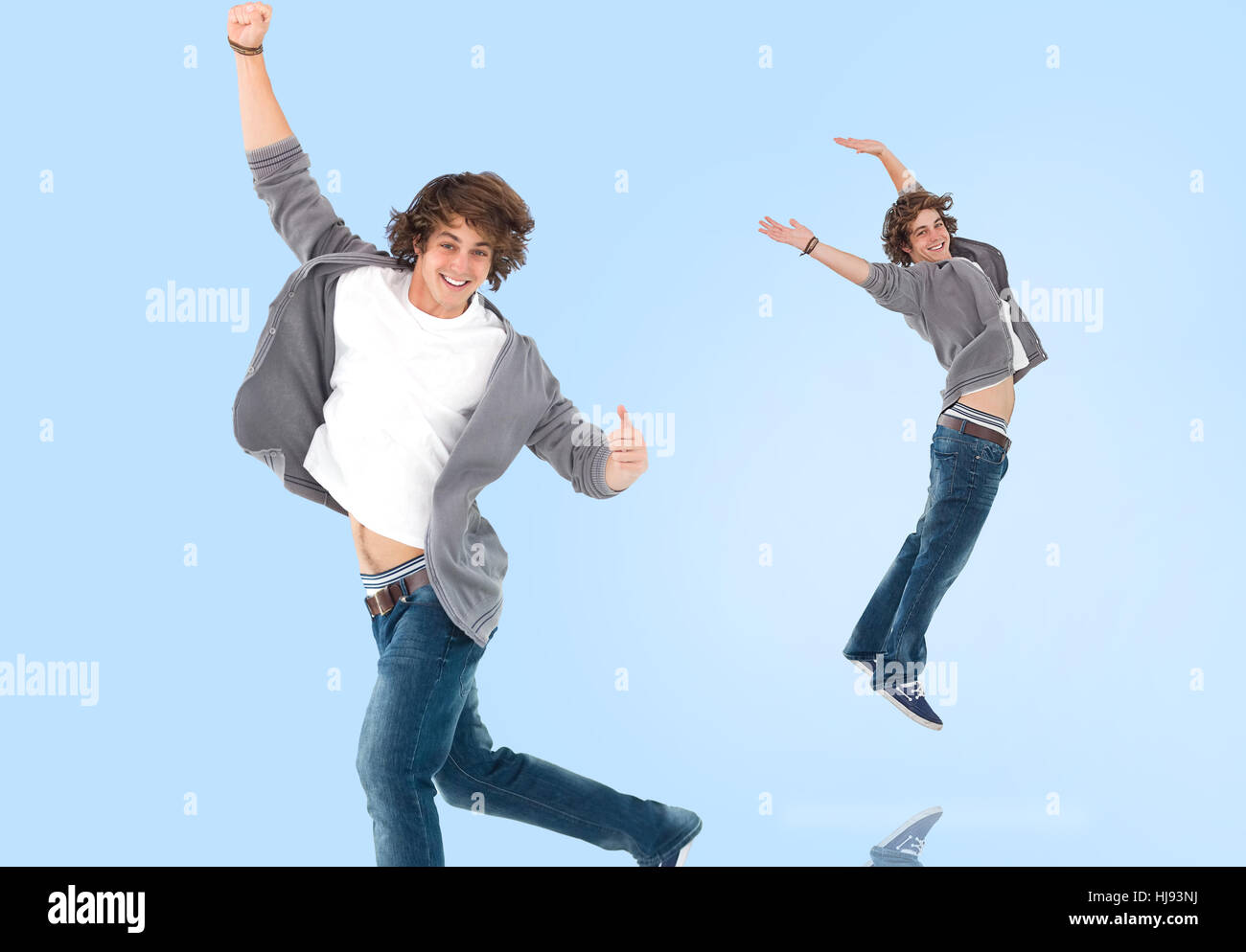 Two of the same teenage boy jumping for joy on blue background Stock ...