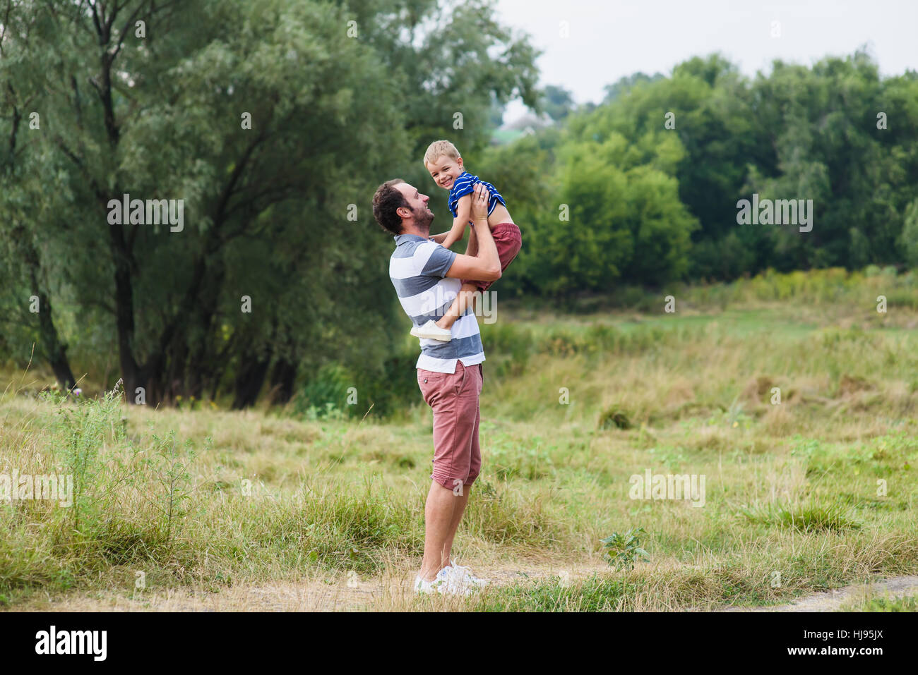 Young father catching his son into hands outdoor. Dad playing with his ...
