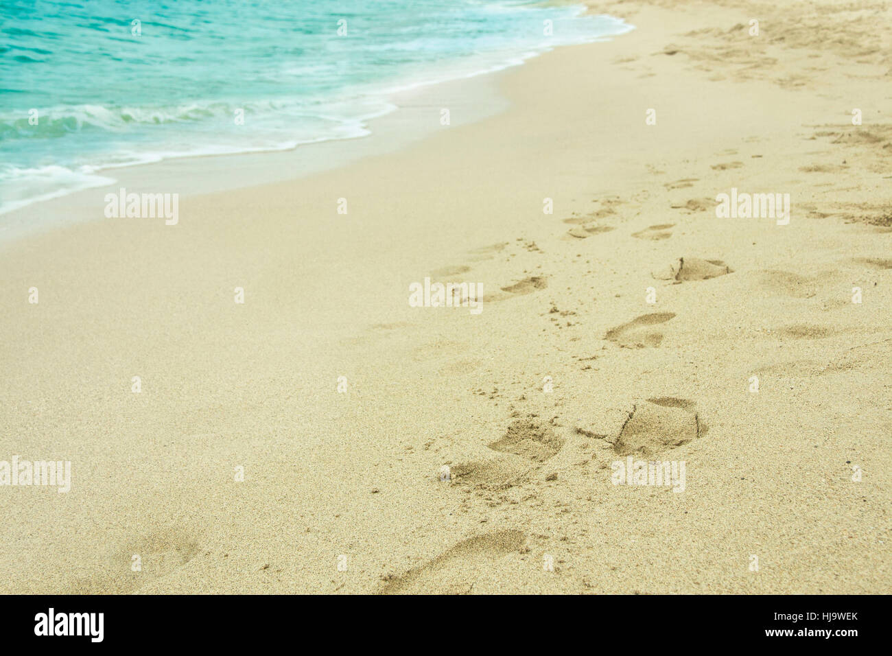 sandy footprints on island tropical beach in middle of sunny day close ...