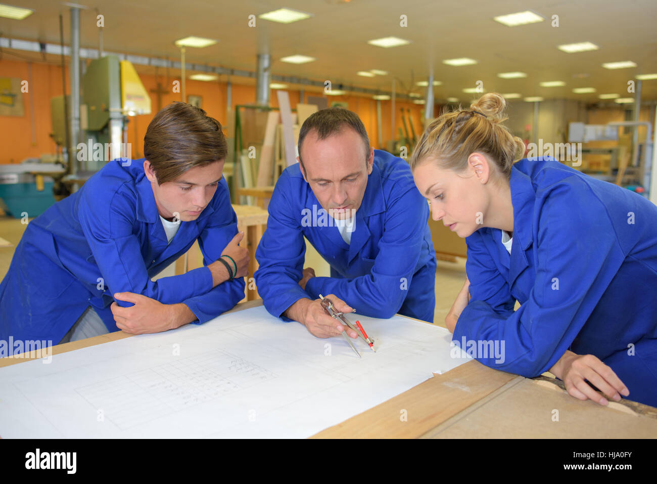 Workers around table looking at paperwork Stock Photo - Alamy