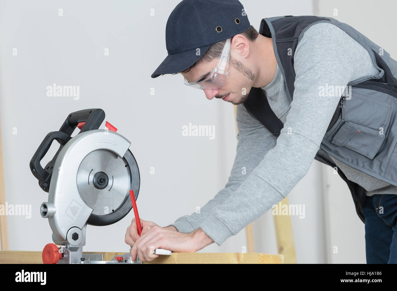 Man marking wood to cut with circular saw Stock Photo - Alamy
