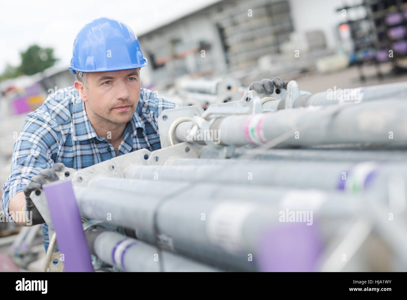Worker pushing stack of scaffolding tubes Stock Photo - Alamy
