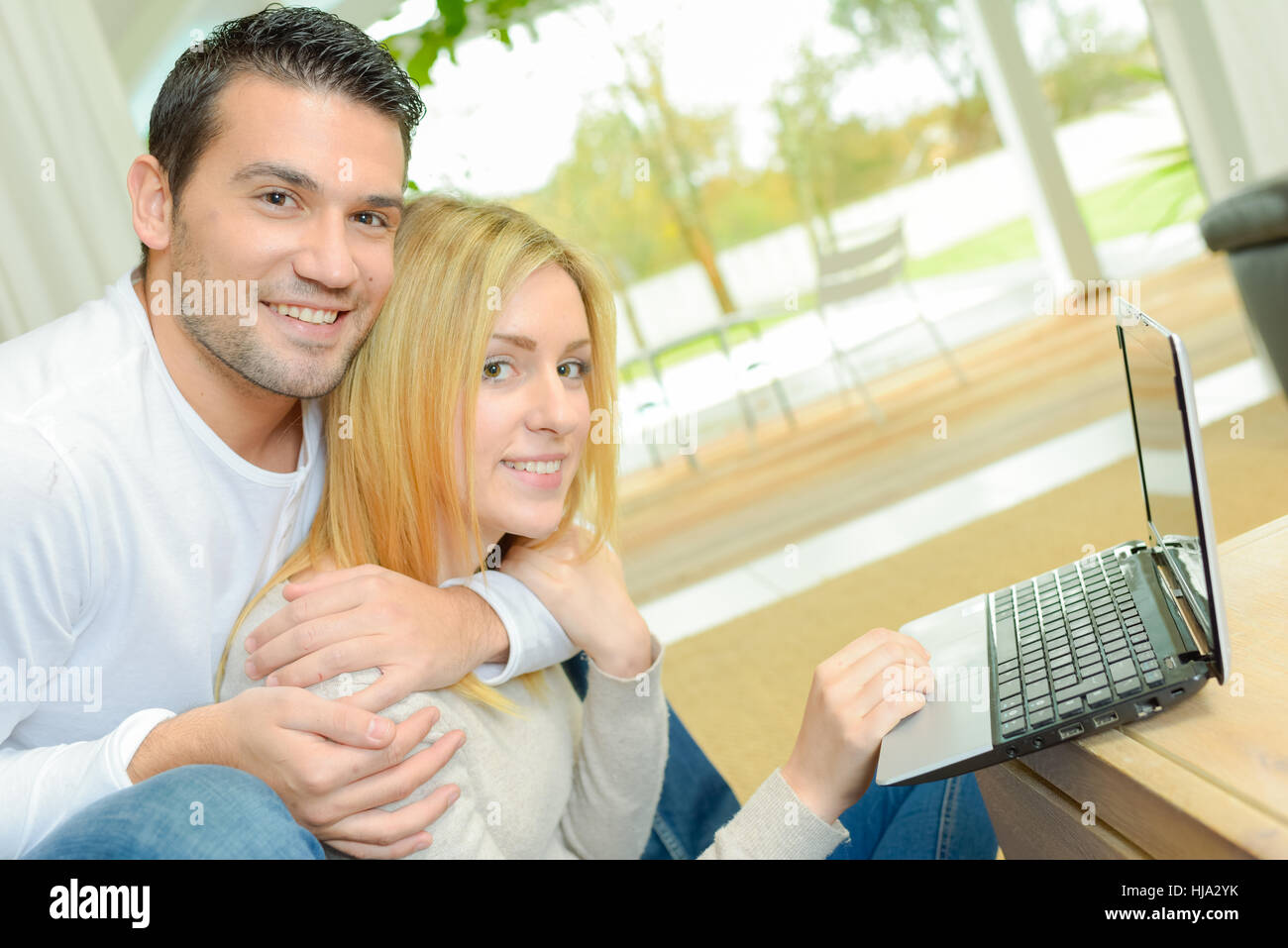 Couple sat at home with a laptop computer Stock Photo - Alamy