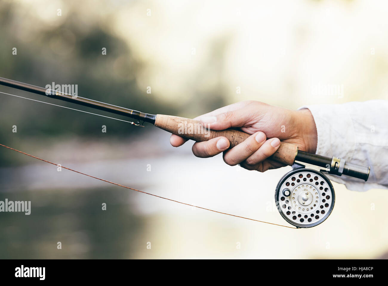 Fly fishing rod in fisherman hand Stock Photo - Alamy