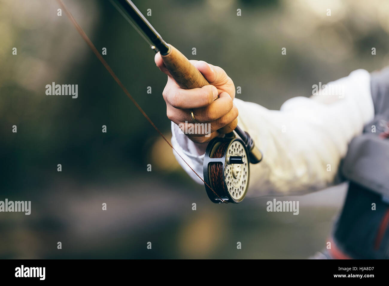 Fly fishing rod in fisherman hand Stock Photo - Alamy