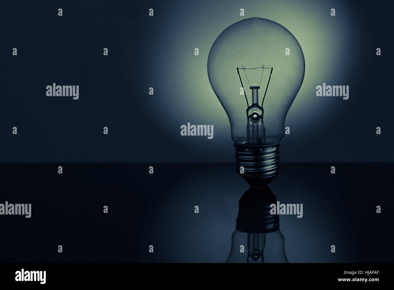 Light bulb standing on bright reflective surface in blue tones Stock ...