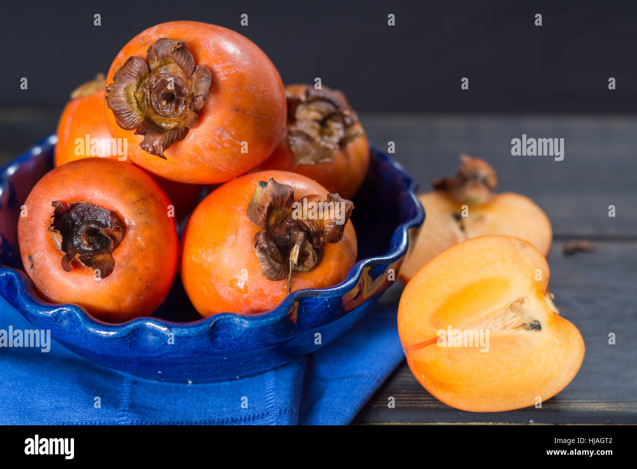 Ripe orange hachiya persimmons in blue bowl Stock Photo - Alamy