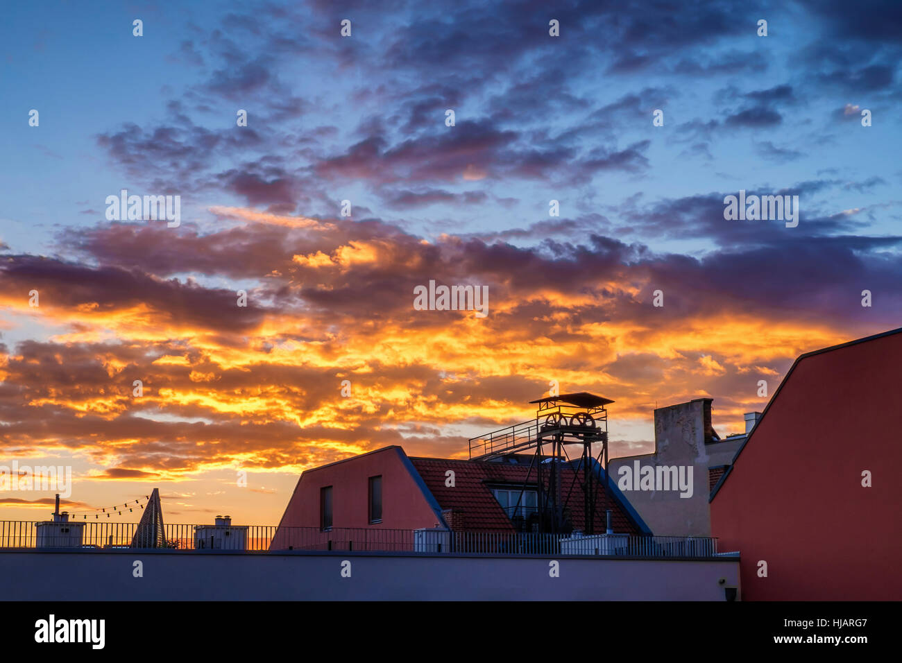 Fiery sunset sky as sun sets at dusk over Rooftop of building with old ...