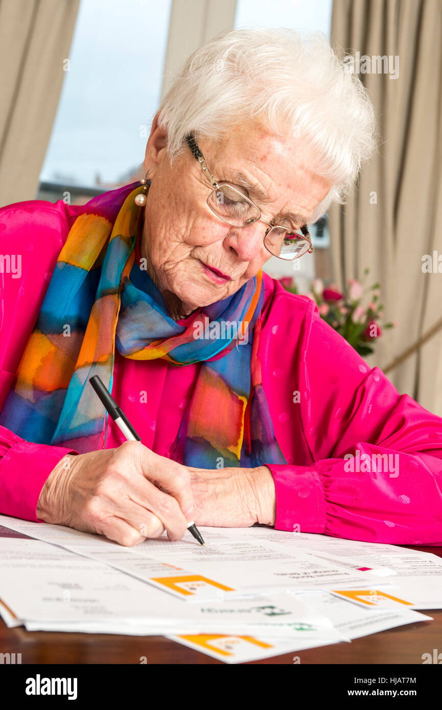 An older lady organising her monthly outgoings in her home in an effort ...