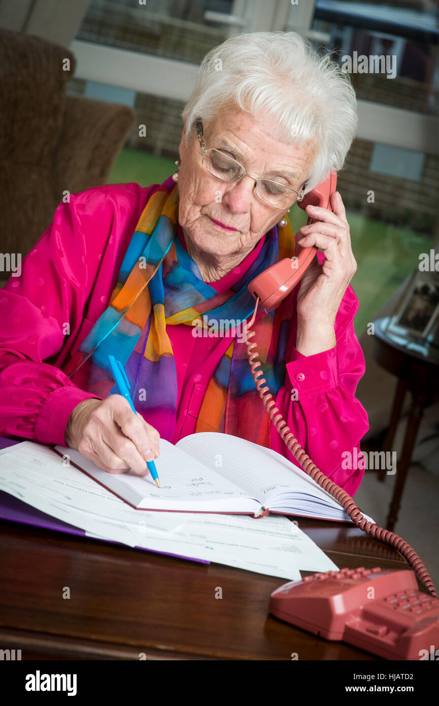 An older lady organising her monthly outgoings in her home in an effort ...