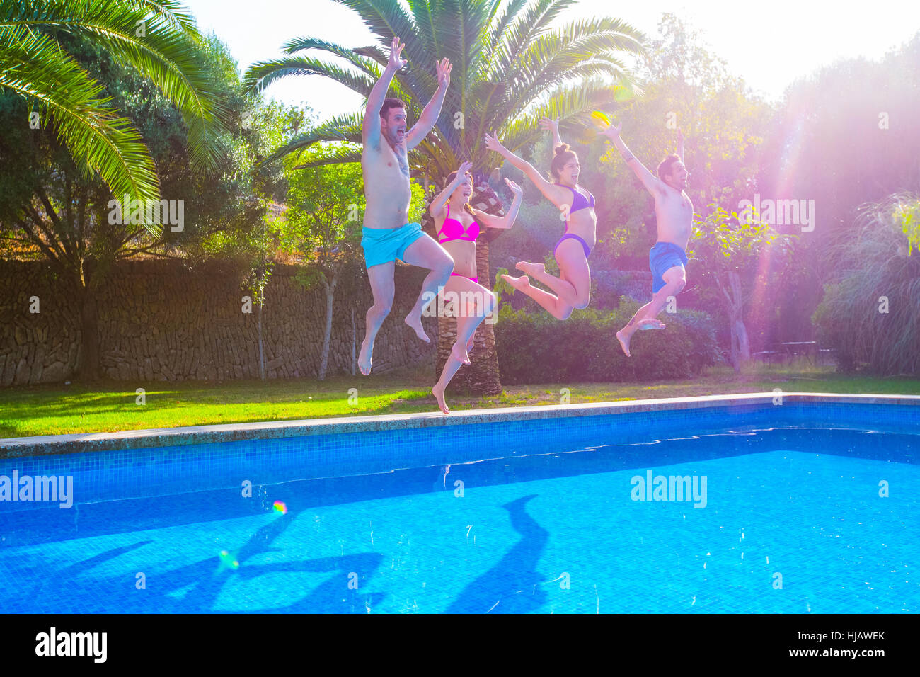 Friends jumping in swimming pool together Stock Photo - Alamy