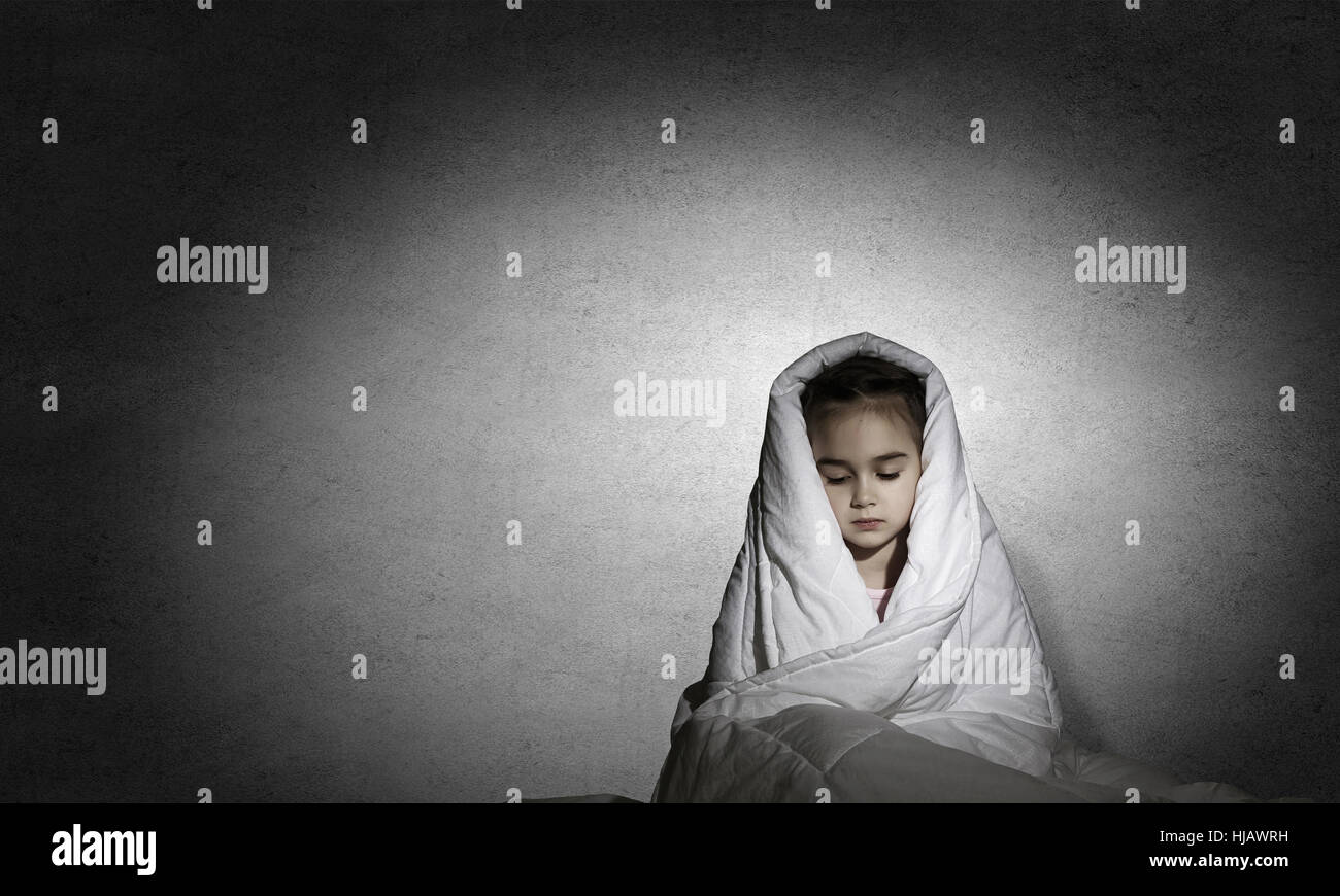 Cute scared girl sitting in bed under blanket Stock Photo - Alamy